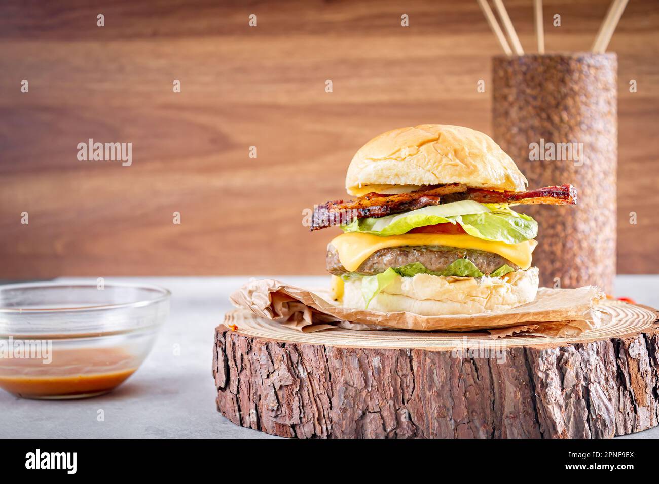 Delicious hamburger with cheddar cheese and bacon over wooden log and ...