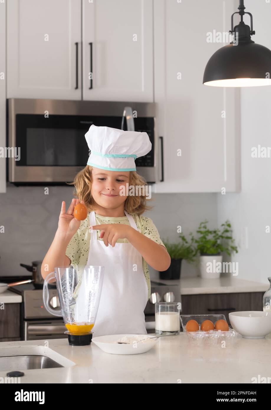 Chef kid boy baking on the kitchen. Child chef cook prepares food at ...