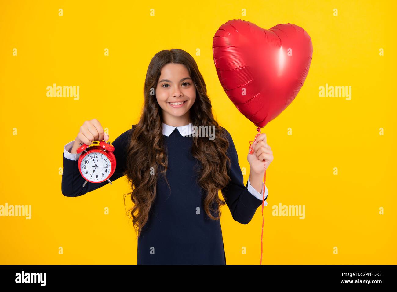 Teenager child hold clock isolated on yellow studio background ...