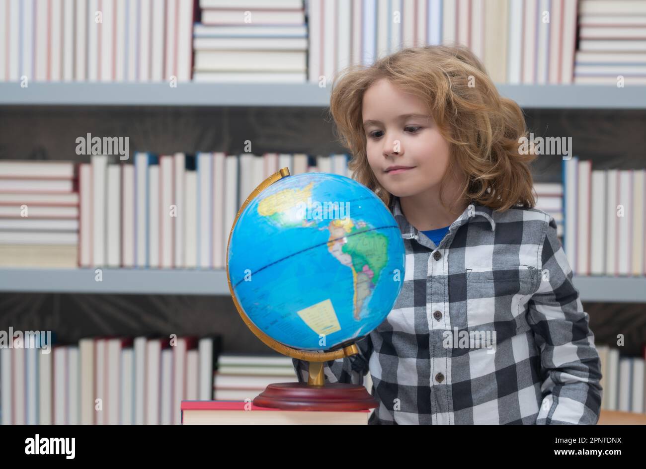 School pupil looking at globe in library, geography lesson. School and ...