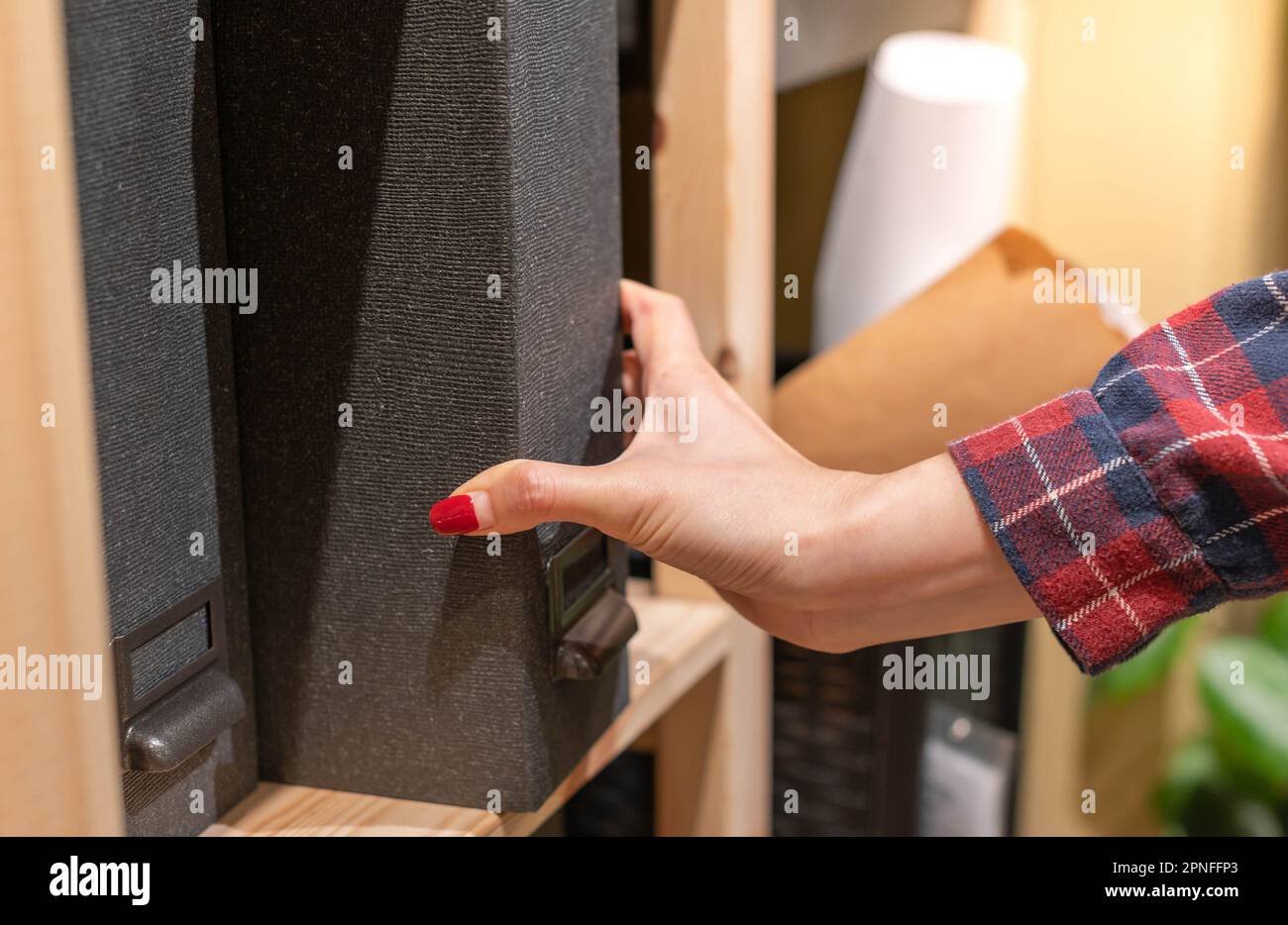Female hand-picking new dark grey file binder on a shelf in stationery ...