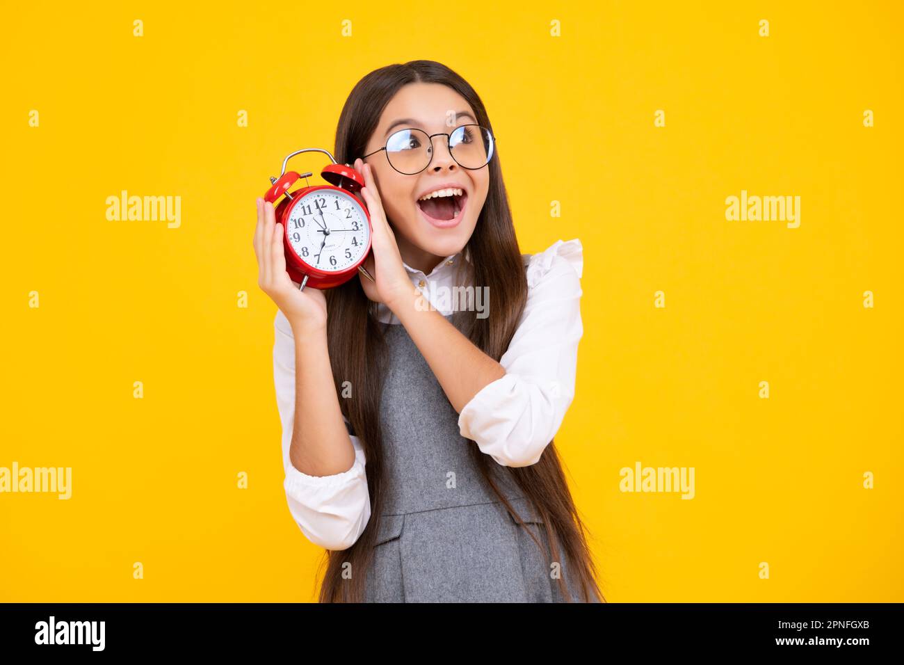 Teen student girl hold clock isolated on yellow background. Time to ...