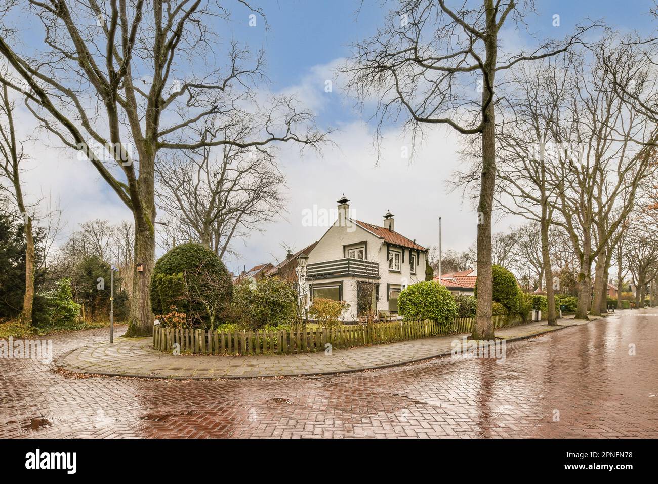 a house in the middle of a street with trees on both sides and a blue ...