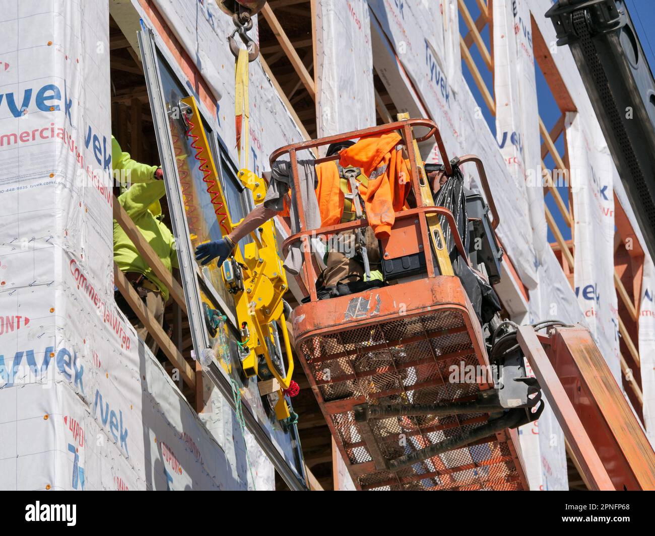 Construction workers installing window in highrise apartment building ...