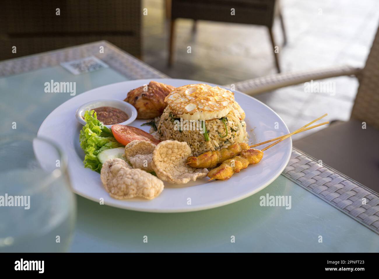 Fried rice served with fried chicken, fried egg and satay. Asian style ...