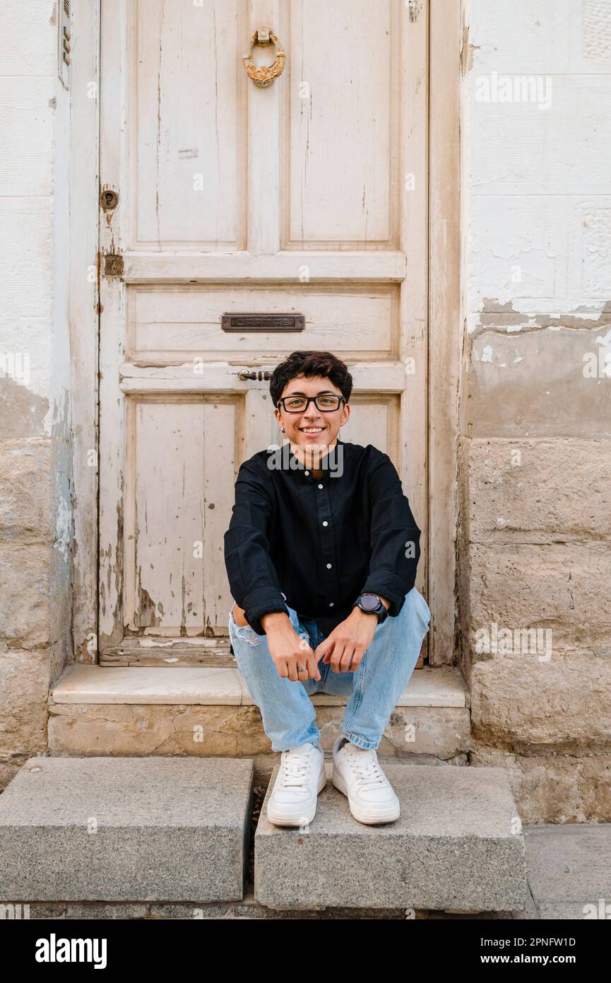 Young transgender man posing sitting on the front steps of a house ...