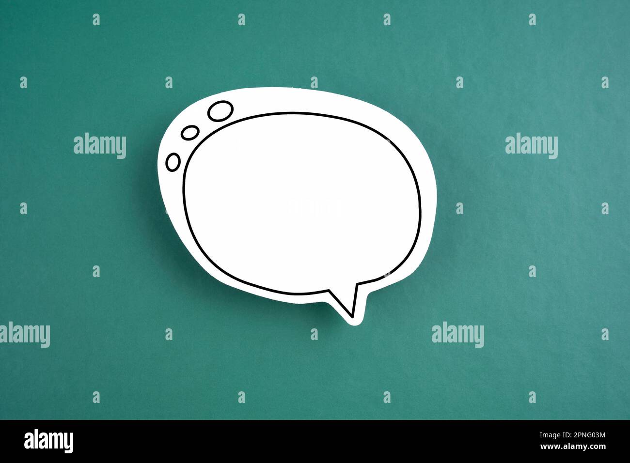 White speech bubble shaped post it note on green background with copy ...