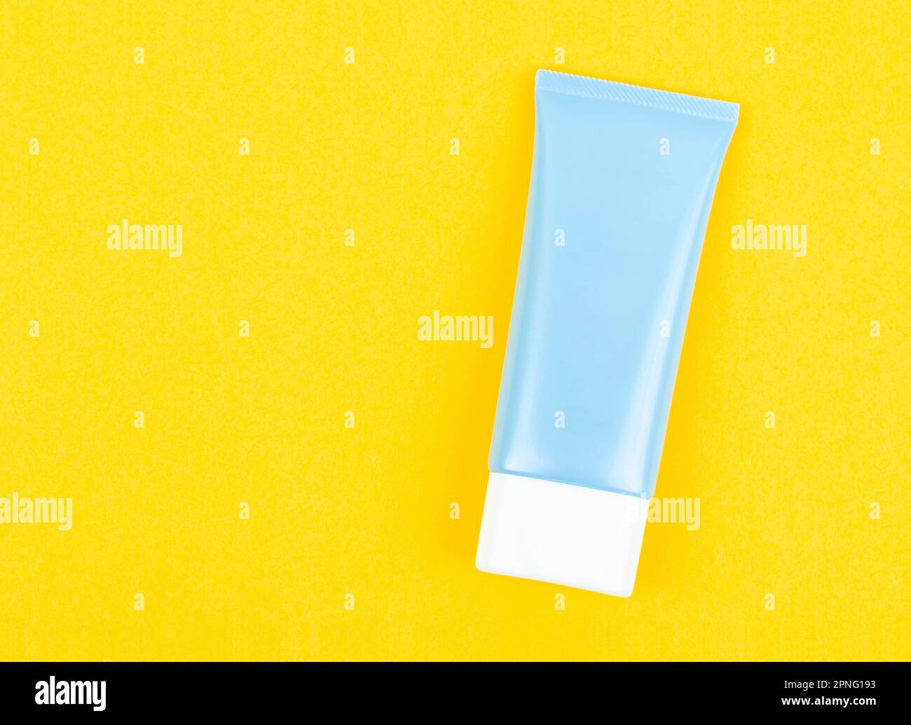 Blue squeeze bottle cosmetic tube on yellow background with copy-space ...