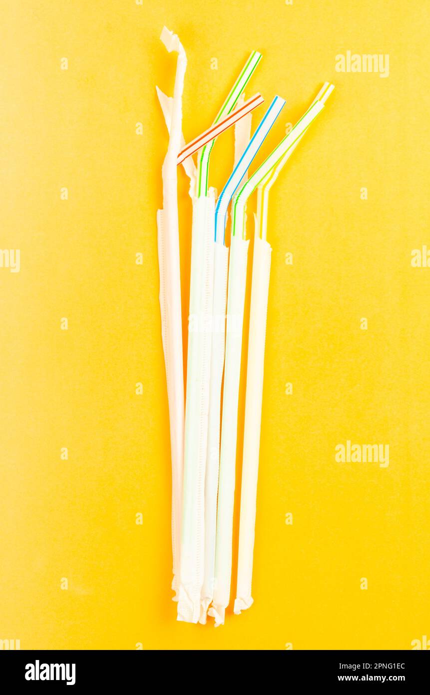 Plastic drinking straws with paper package on yellow background ...