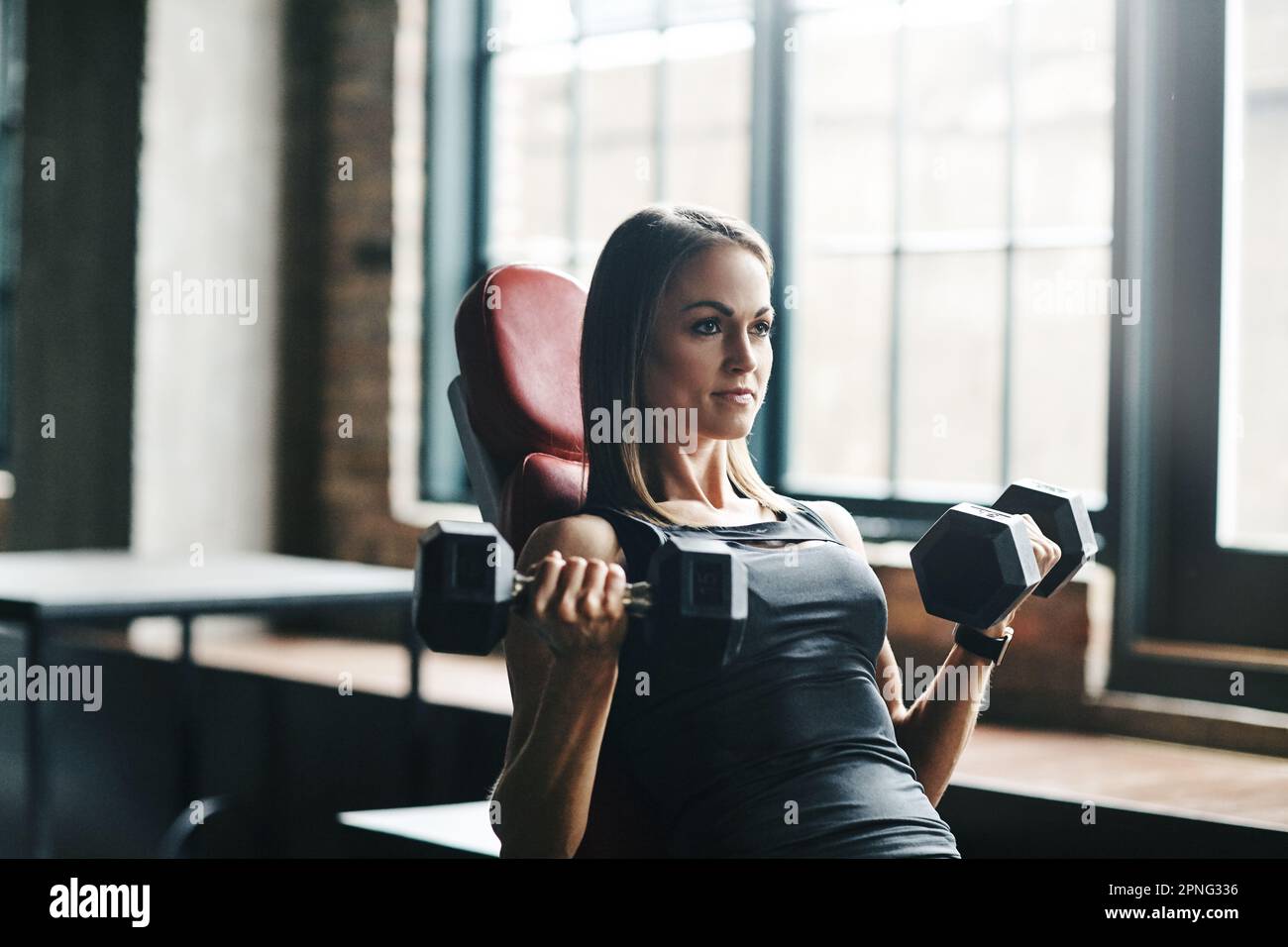 Getting a good grip on her fitness goals. a young woman working out with weights in a gym Stock ...