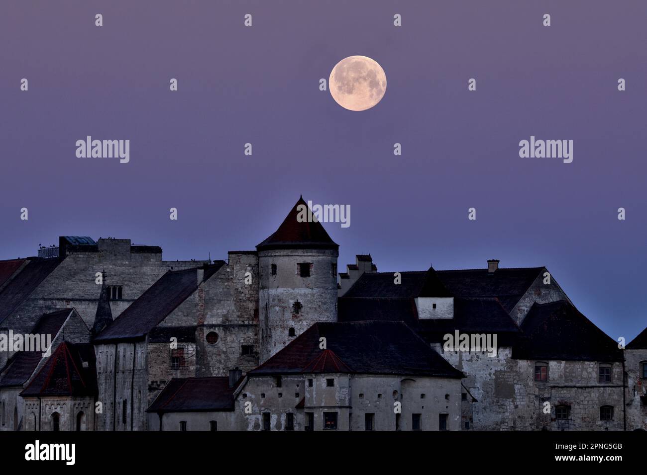 The full moon sets behind the castle in Burghausen, blue morning light ...