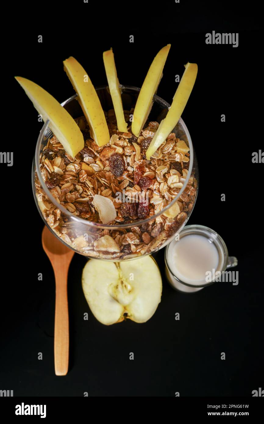Glass cup with muesli, apple and milk isolated on black background ...