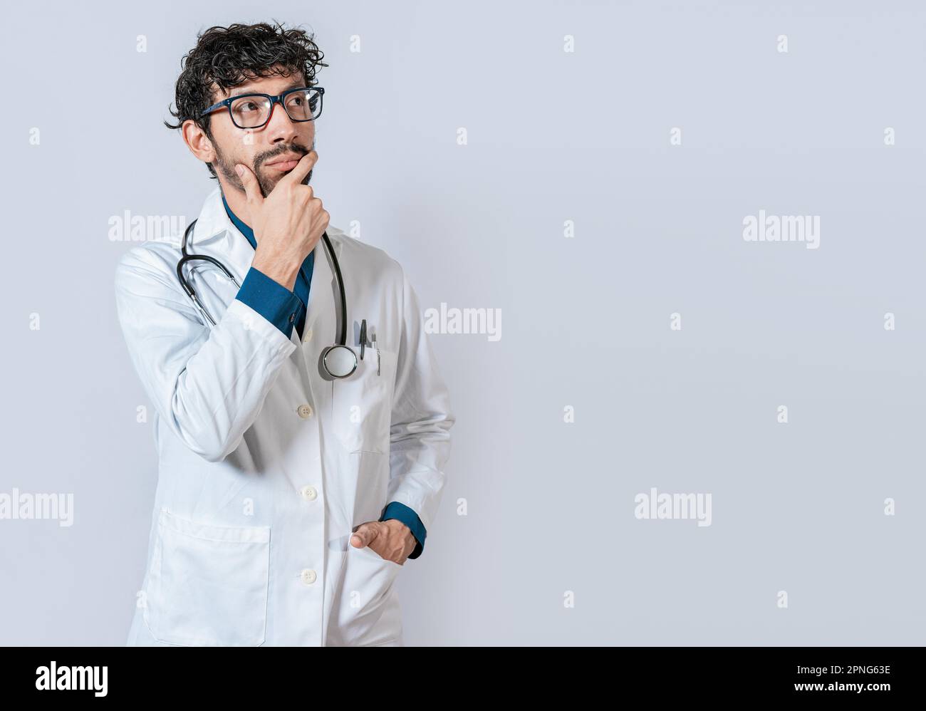 Doctor thinking with hand on chin. Young doctor thinking and looking up ...