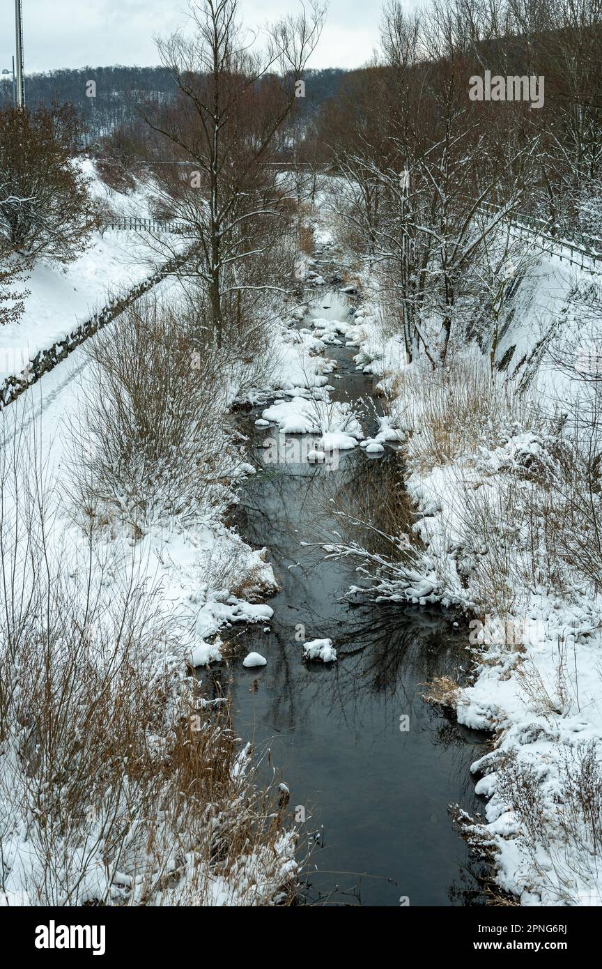 A small river in a regulated streambed and a wintry landscape. There ...