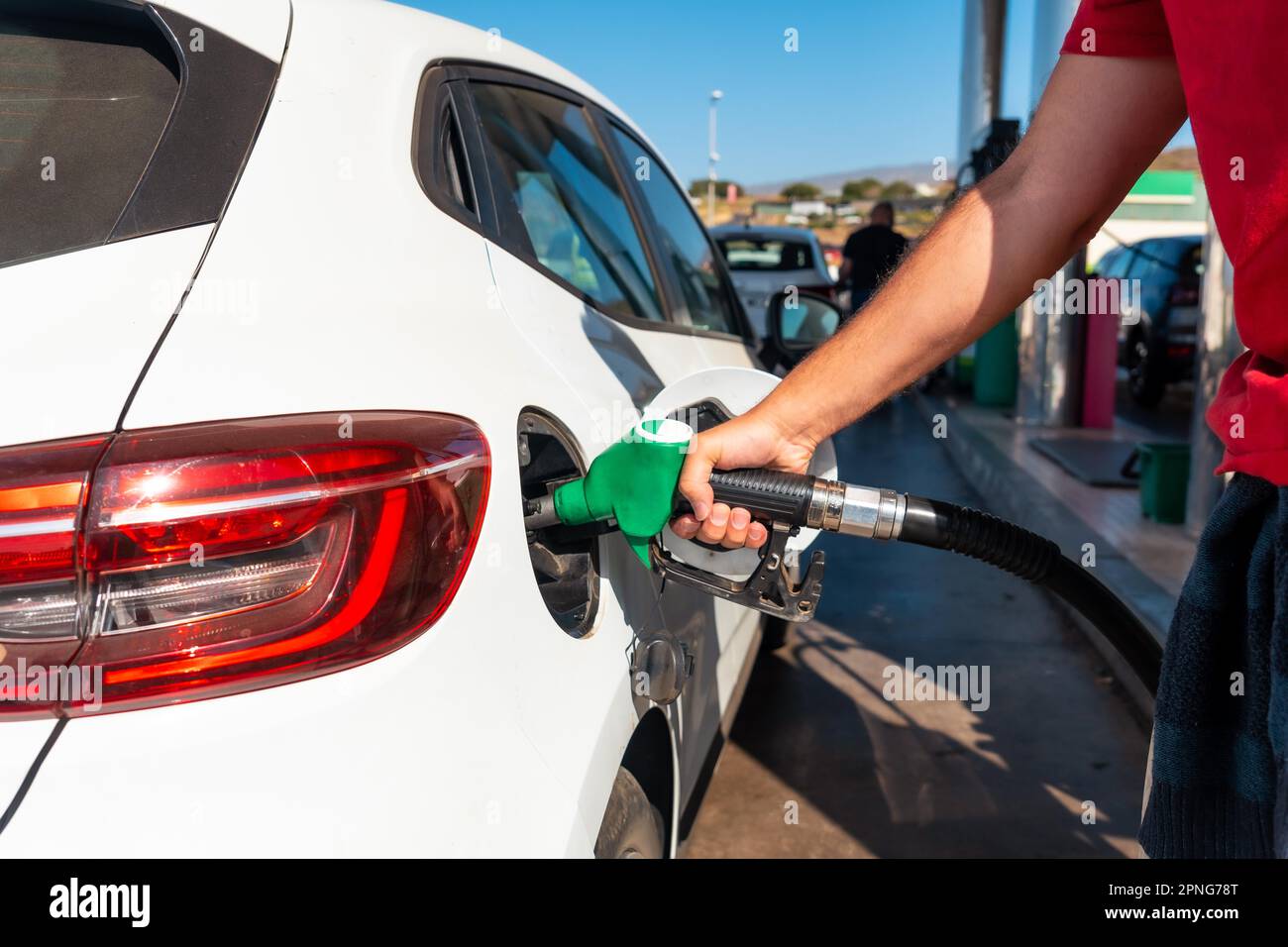 Man with the gun refueling gasoline or diesel fuel in a white car ...