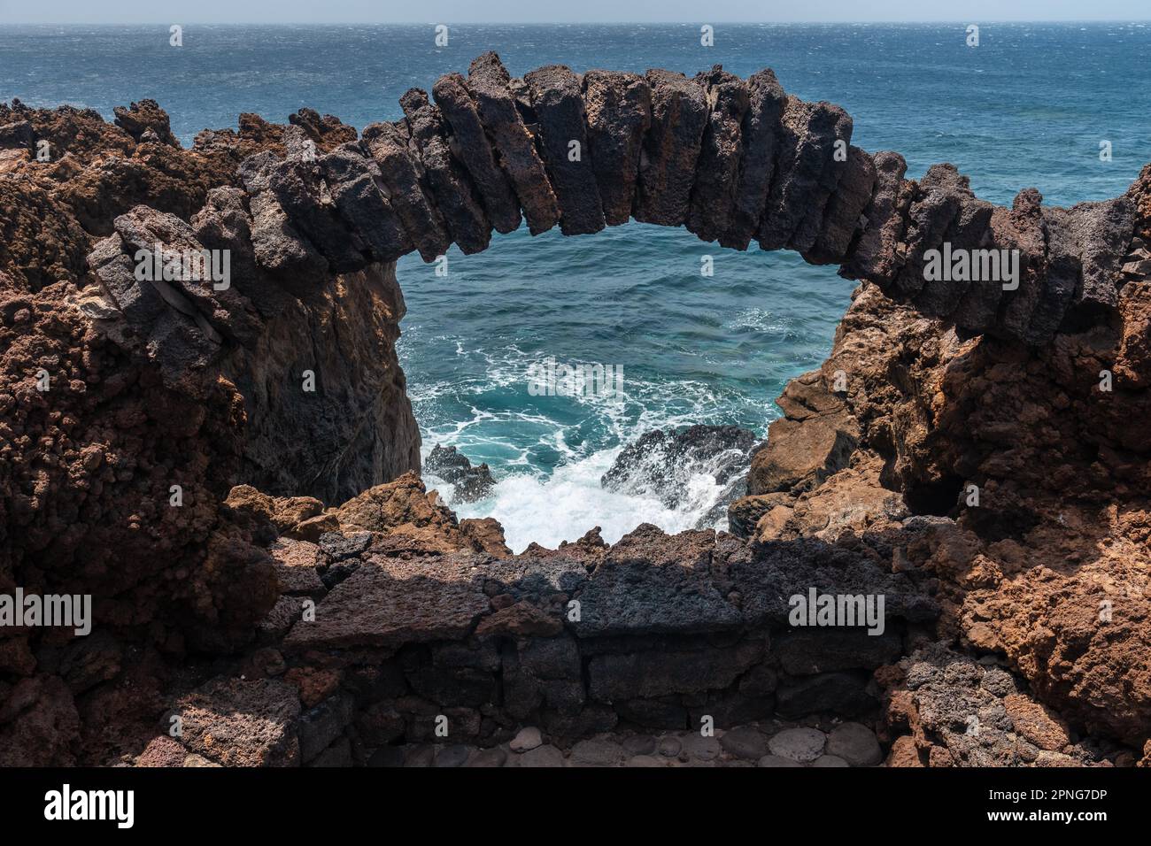 An arch of volcanic stones in the sea on the Verodal beach on El Hierro ...