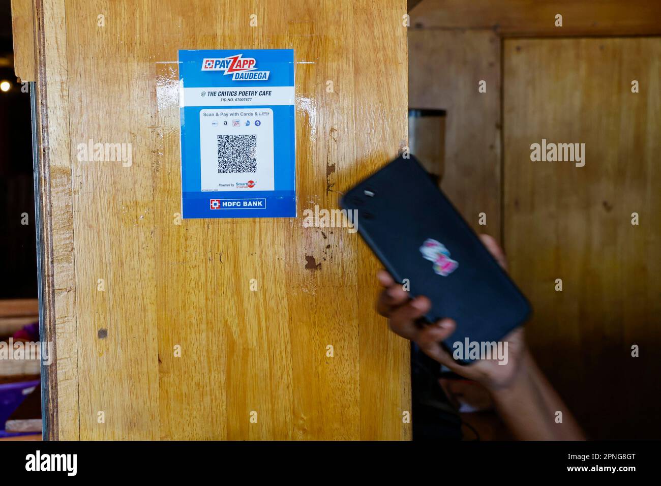 A hand holds a mobile phone to a QR code for cashless payment at the ...
