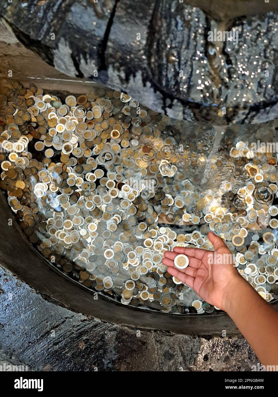 Hands of small children with coins that are thrown into a fountain where they ask for wishes ...
