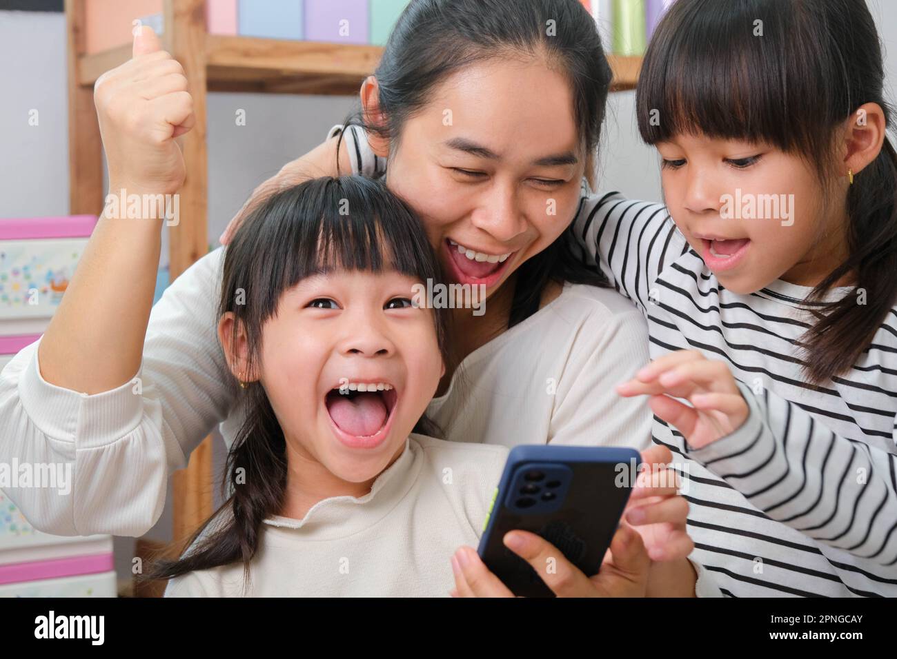 Mother and daughter playing and hugging, taking selfies on smartphones ...