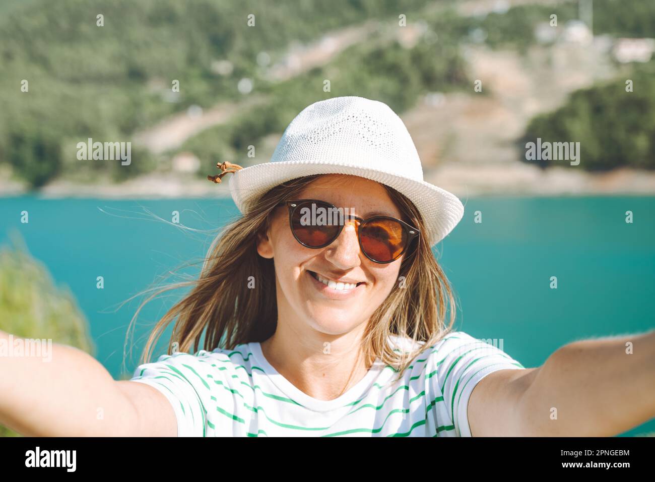 Woman taking selfie photo with wide angle front camera of mountains ...