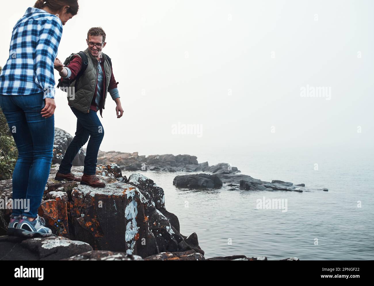 Making their way to the other side. a couple crossing over rocks while ...