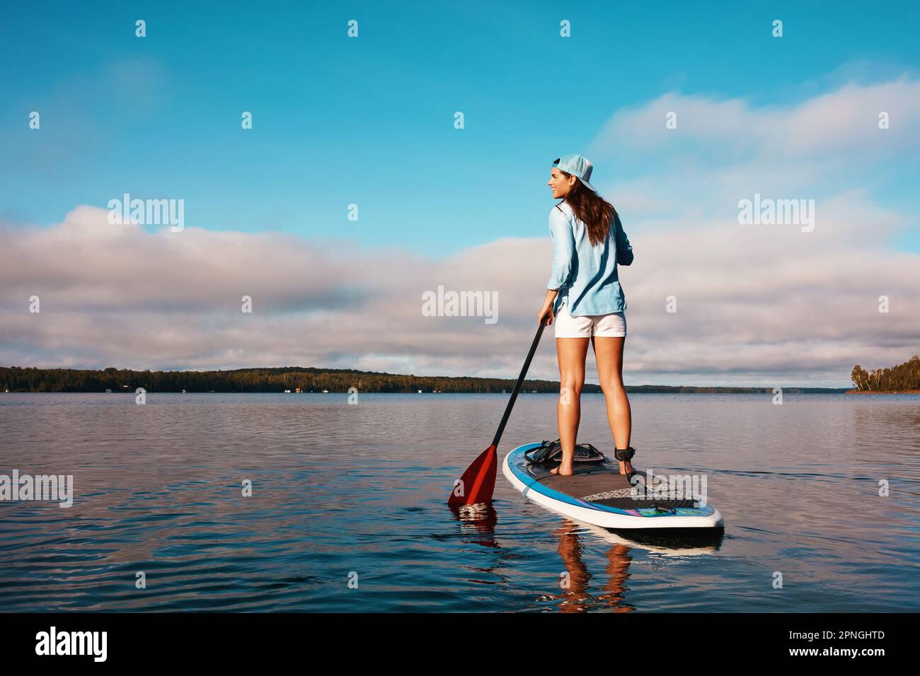 The beauty out here is breathtaking. a young woman paddle boarding on a ...