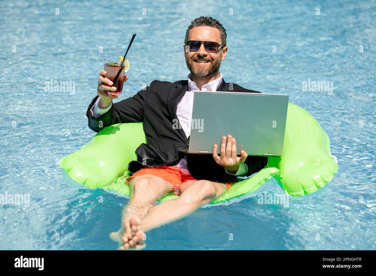 Funny business man in a business suit floating in the water in the pool ...
