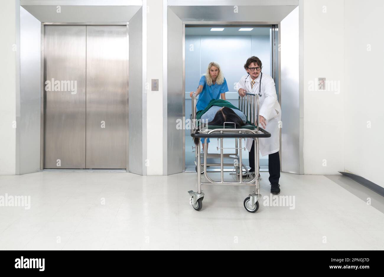 Paramedic and nurse pushing the patient bed out of the elevator to the ...