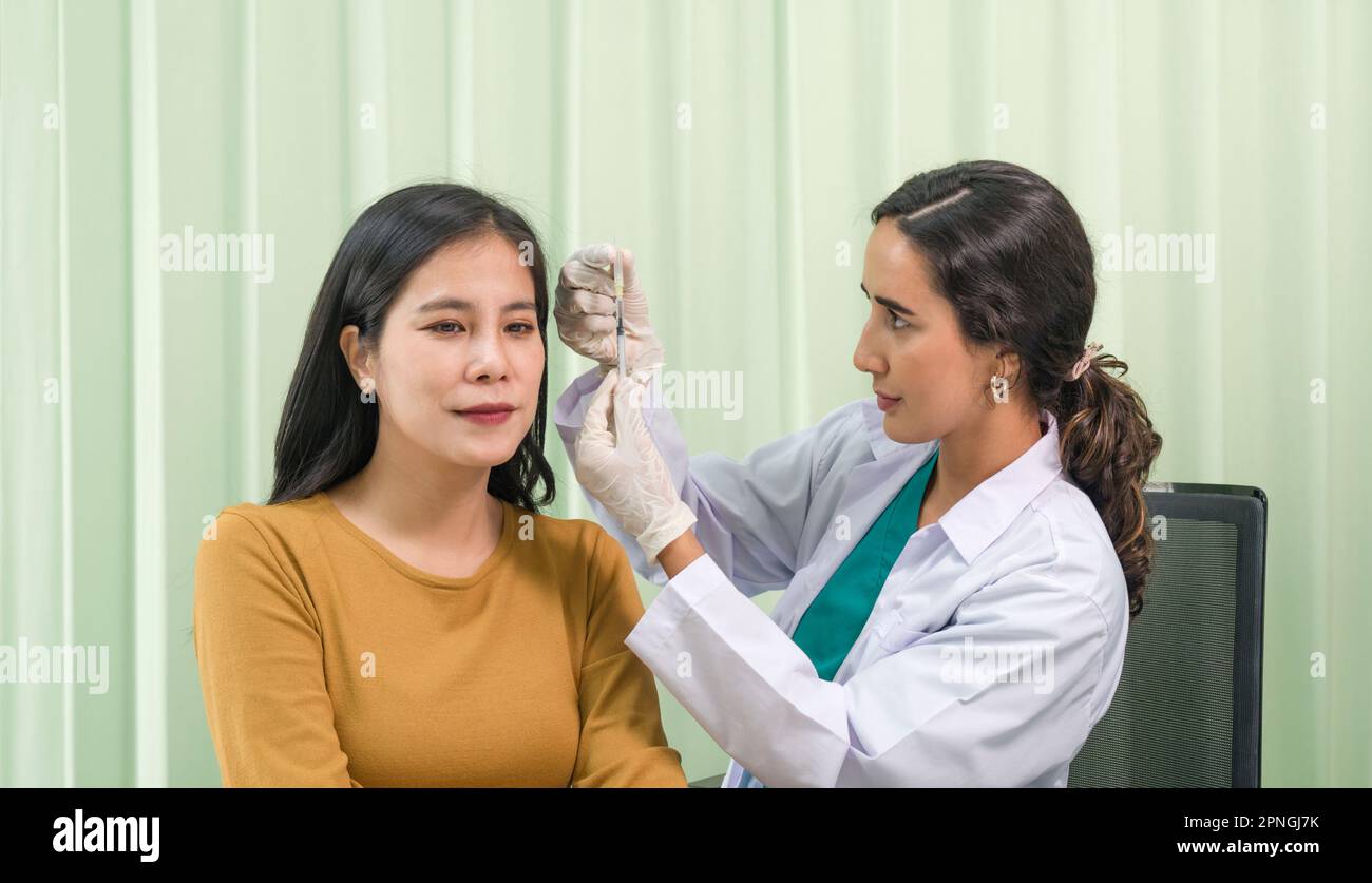 Doctor in white gown and protective glove prepares to give an injection ...