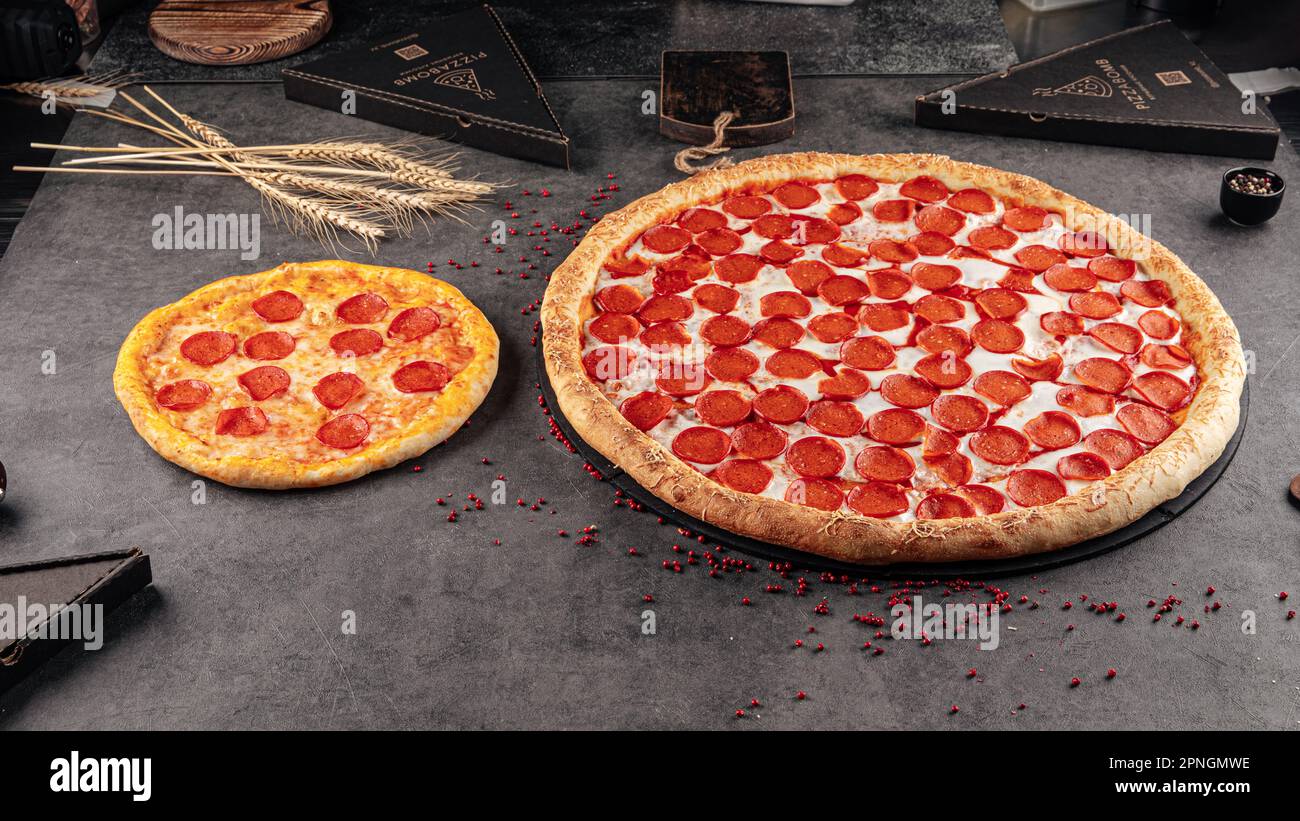 Side view on small and giant pepperoni pizzas Stock Photo - Alamy