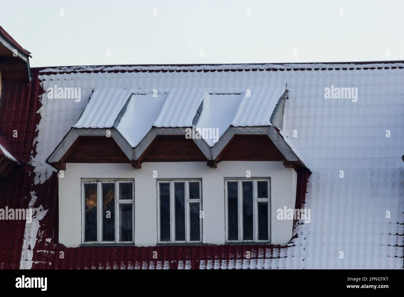 Snow on the roof of a red, brown metal roof of a European house with a ...