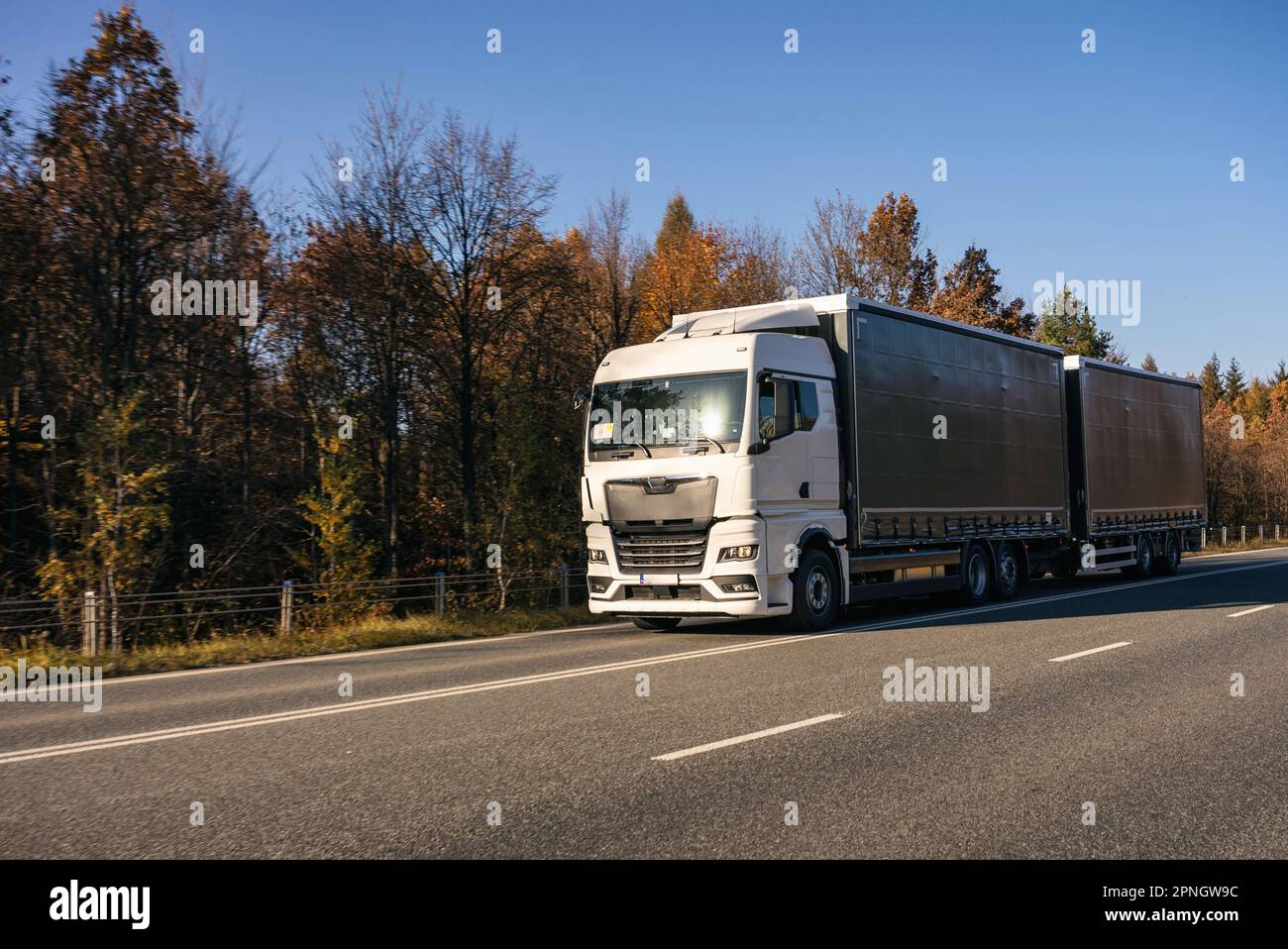 Truck is driving through the forest in autumn. Truck with semi-trailer ...