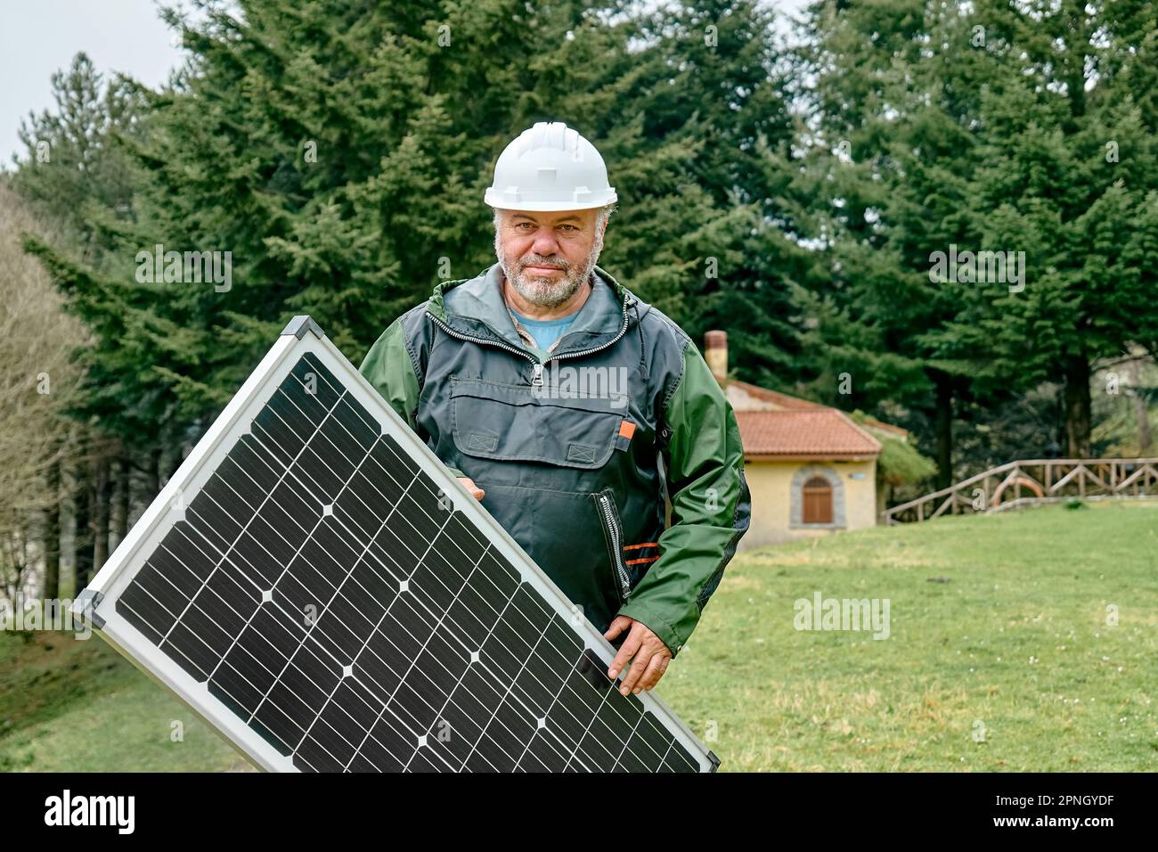 Middle aged bearded technician with voltaic solar panel near house in ...