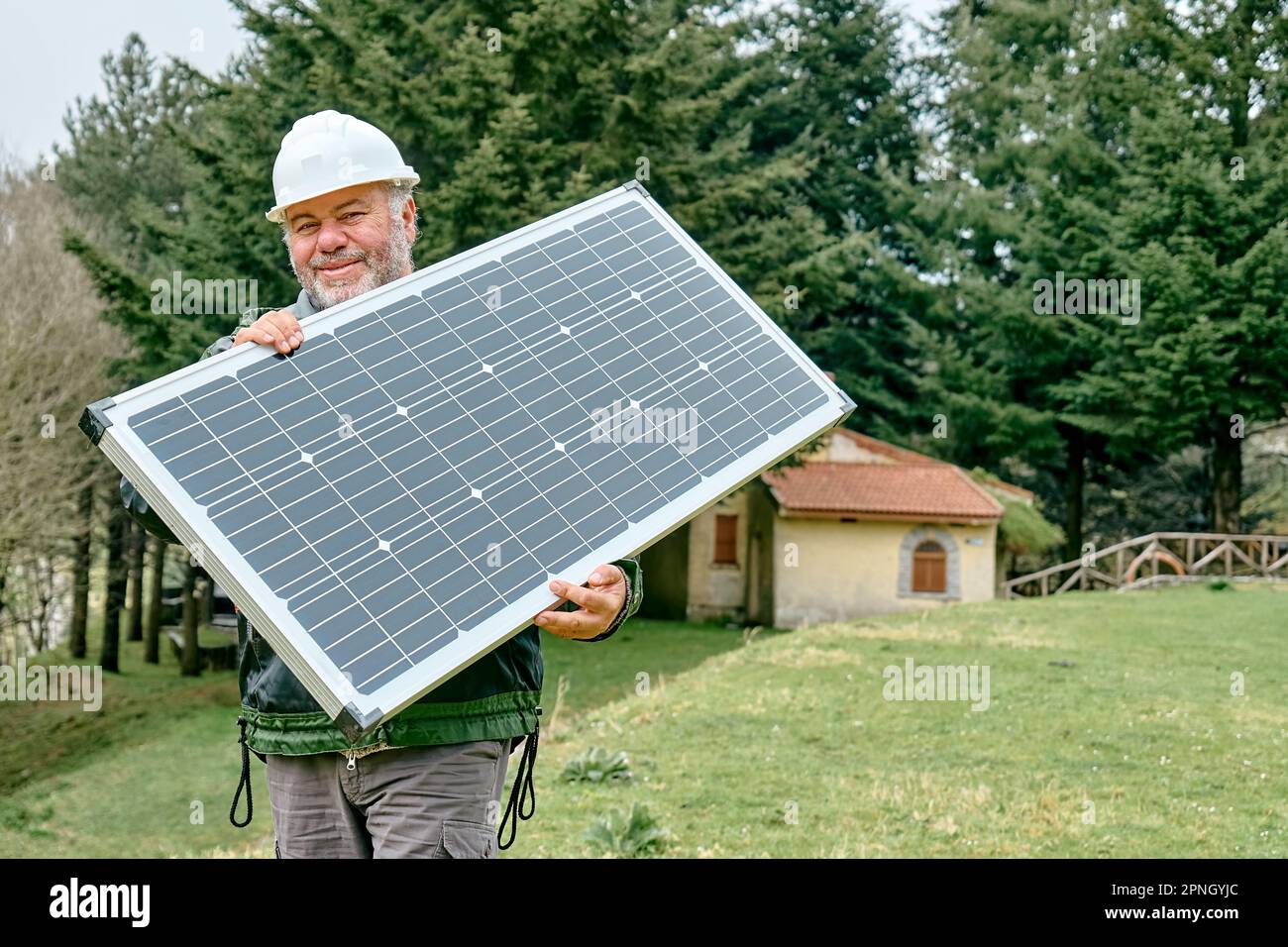 Middle aged bearded technician with voltaic solar panel near house in ...