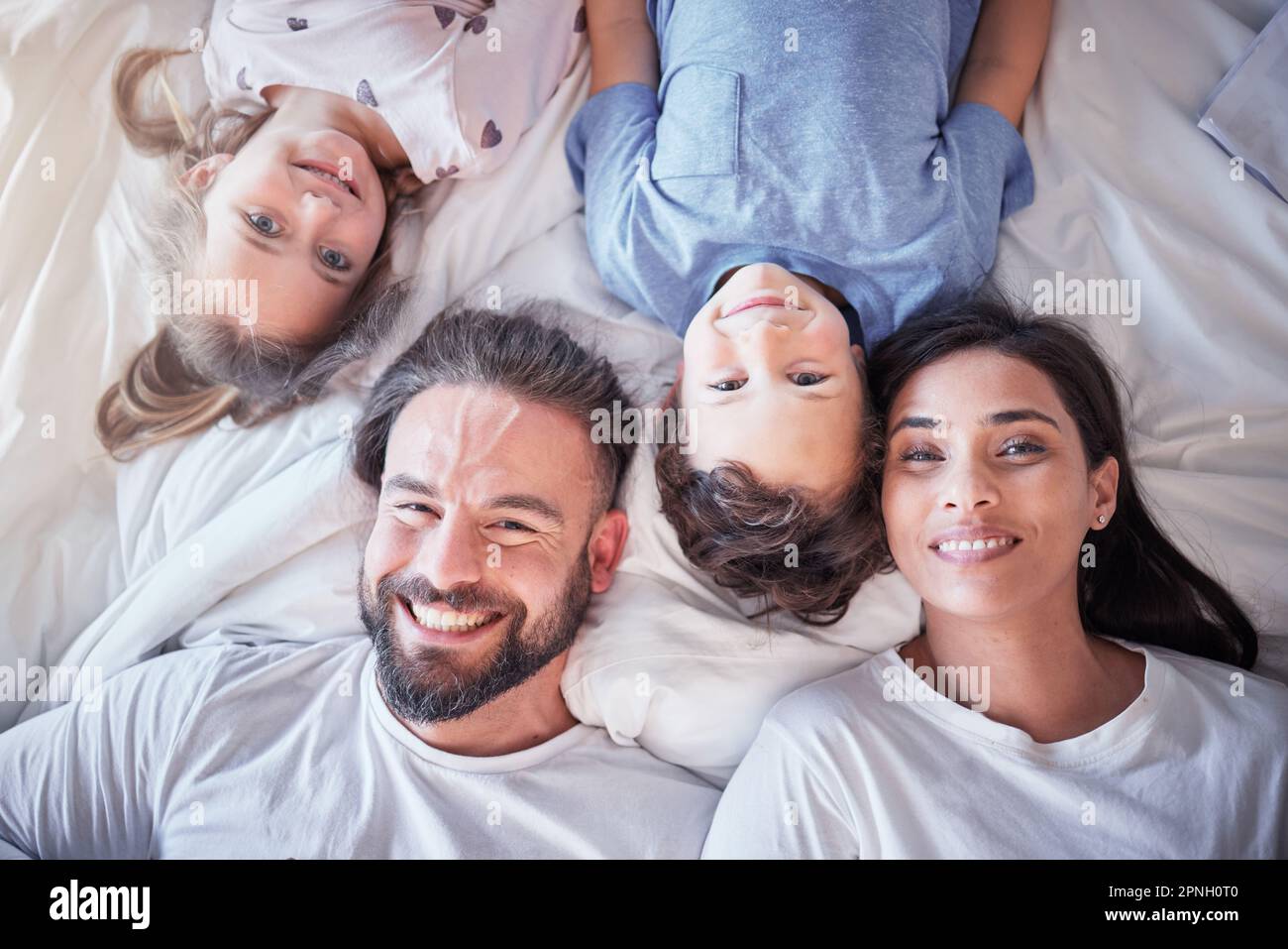 Top view, smile and family on bed, love and bonding with quality time ...