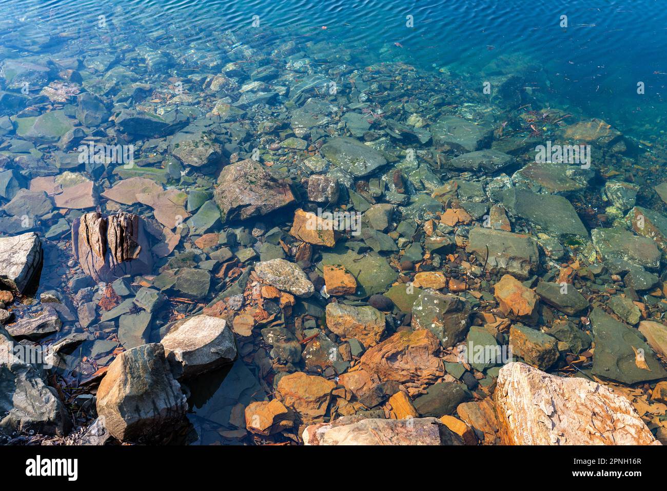 Stones and pebbles visible through the water. Coastal feature Stock ...
