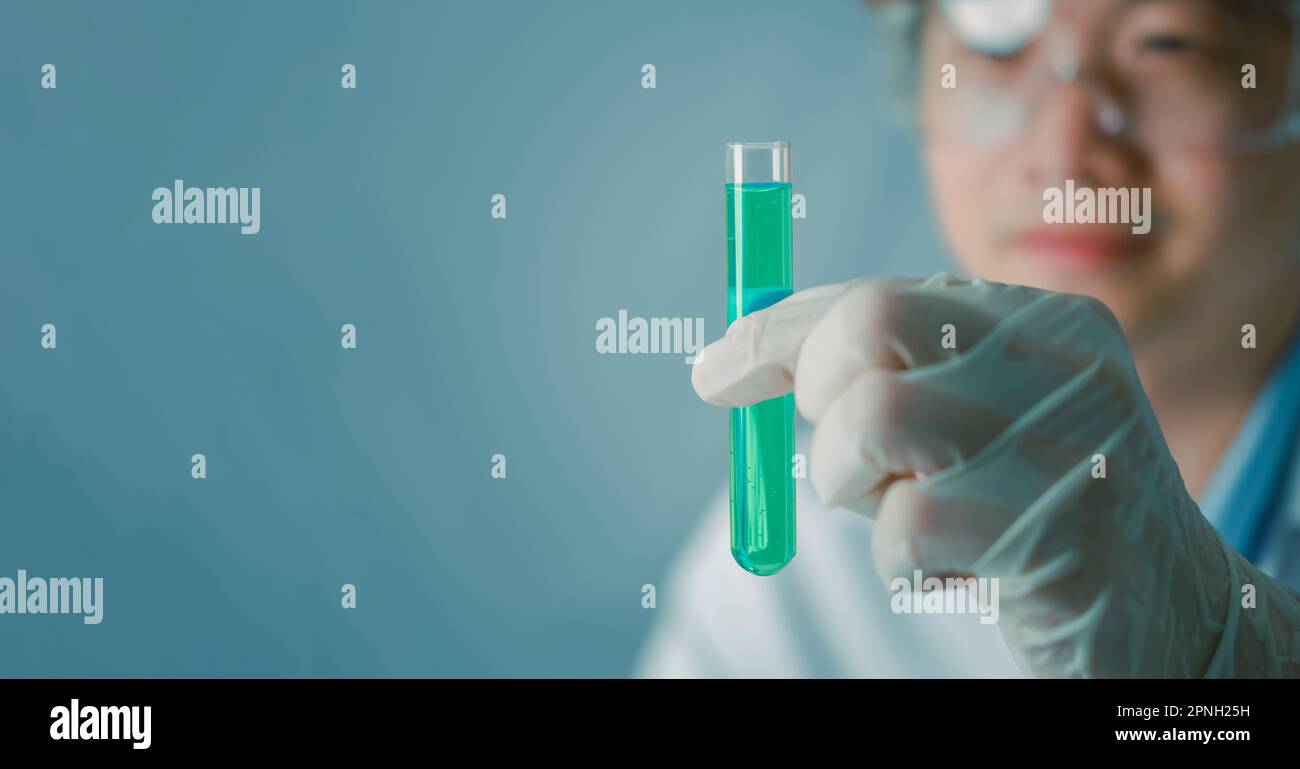 Young asian male scientist hand holds test tubes filled with green ...
