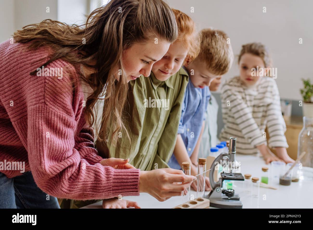 Young teacher doing chemistry experiment with pupils during science ...