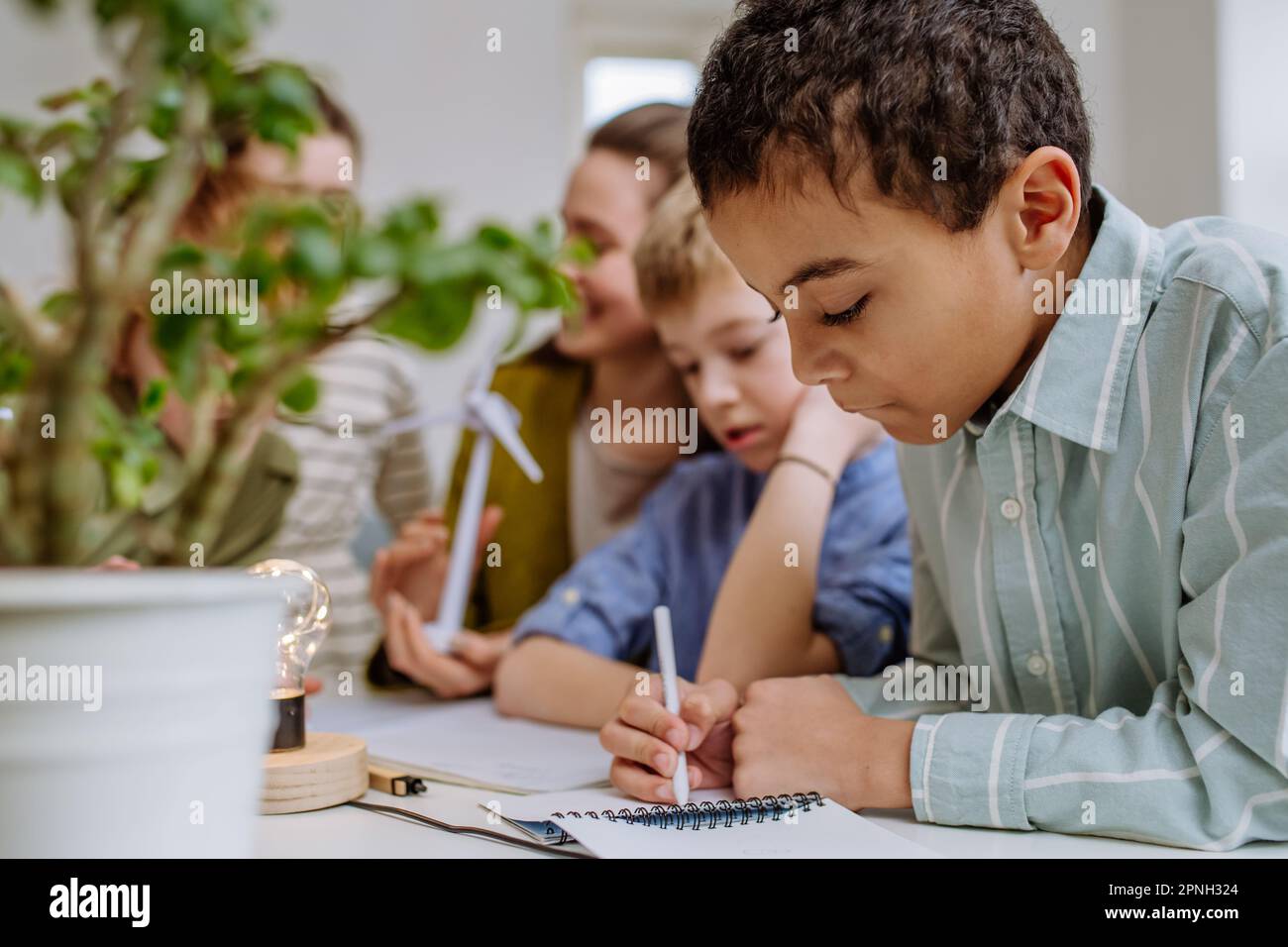 Young Teacher With Model Of Wind Turbine Learning Pupils About Wind