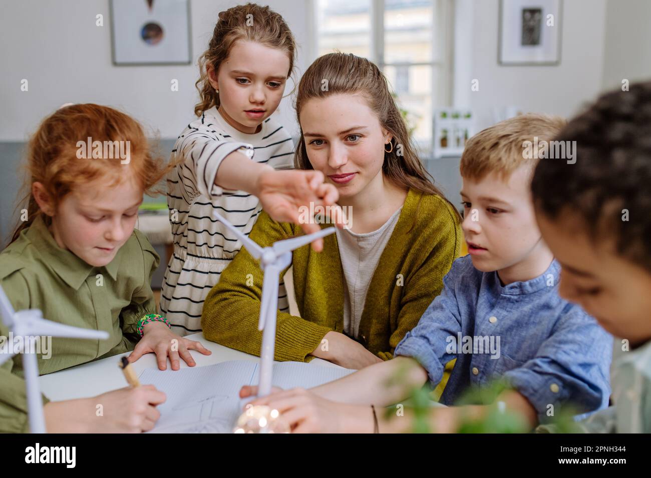 Young Teacher With Model Of Wind Turbine Learning Pupils About Wind