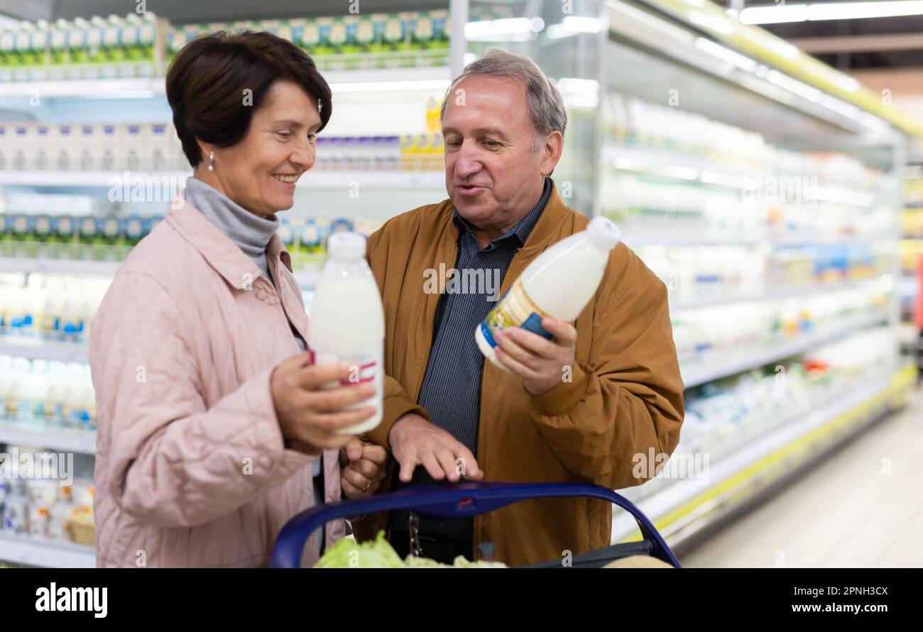 Elderly man and elderly woman choose milk in supermarket Stock Photo ...
