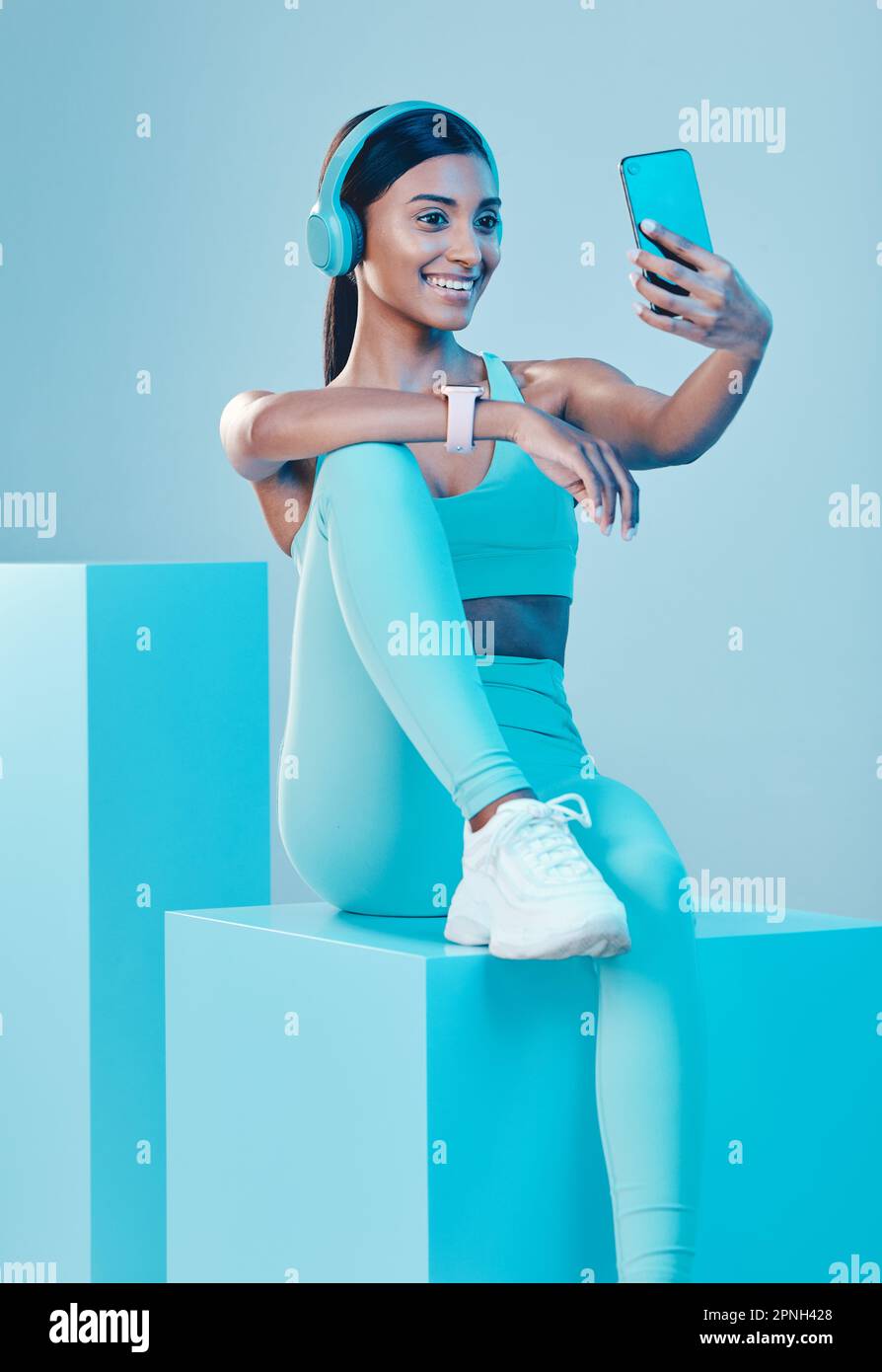 Woman, fitness and selfie in studio with headphones, wellness and ...