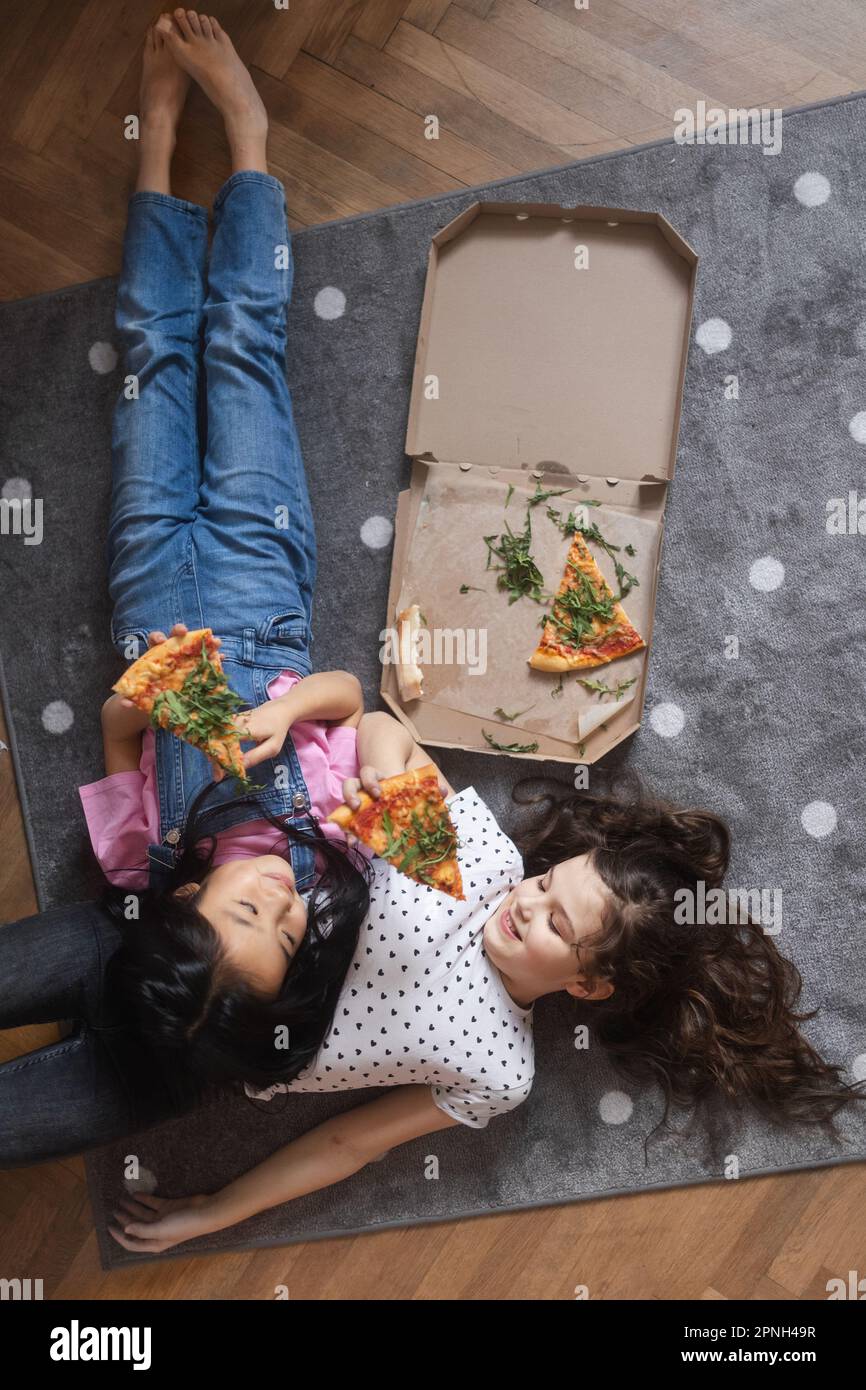 Happy friends lying on a floor and eating pizza Stock Photo - Alamy