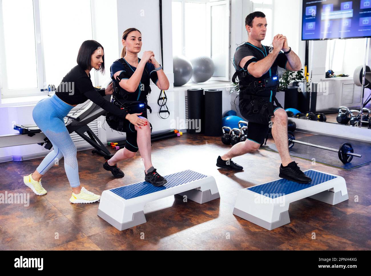 Young sport couple in ems costumes has workout with personal trainer in ...
