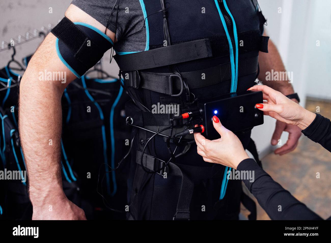 Female trainer hands fix the necessary equipment on ems suit to male ...