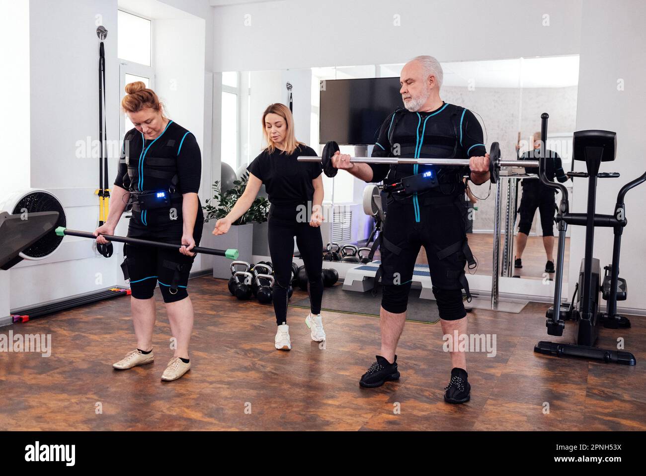 Older sports couple doing electrical muscle stimulation workout in gym ...