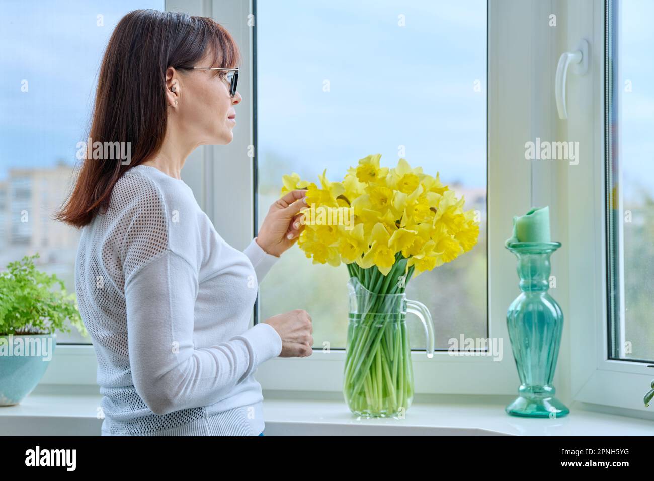 Middle-aged serious pensive woman looking out the window Stock Photo ...