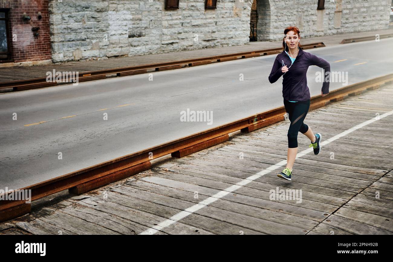 Running makes her feel the most alive. a sporty young woman listening ...