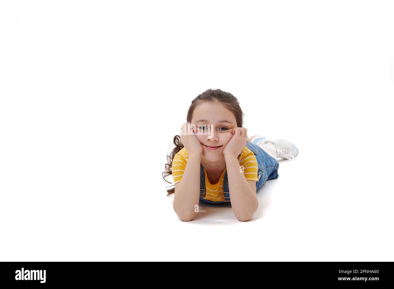 Caucasian little girl in yellow t-shirt and denim sundress lying on ...
