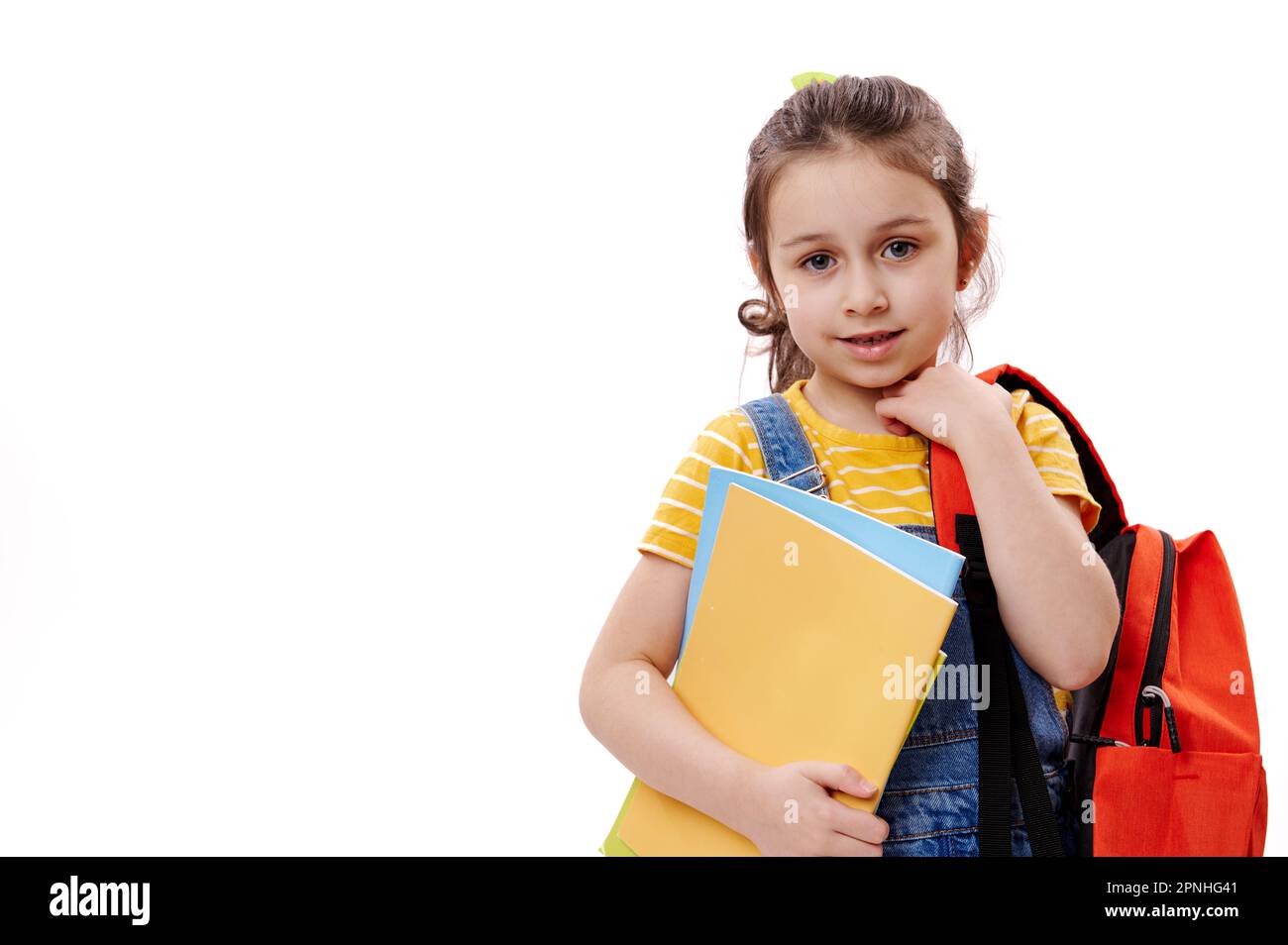 Horizontal portrait of Caucasian first grader schoolgirl, holding books ...